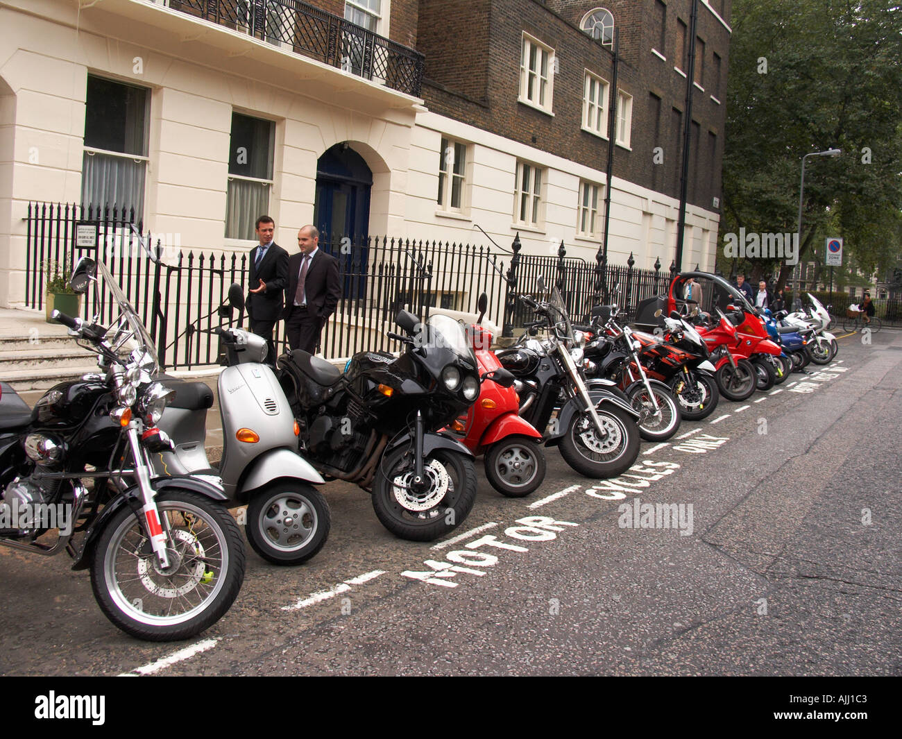 Two men walk past motorcycles parked in motorcycle parking space on ...