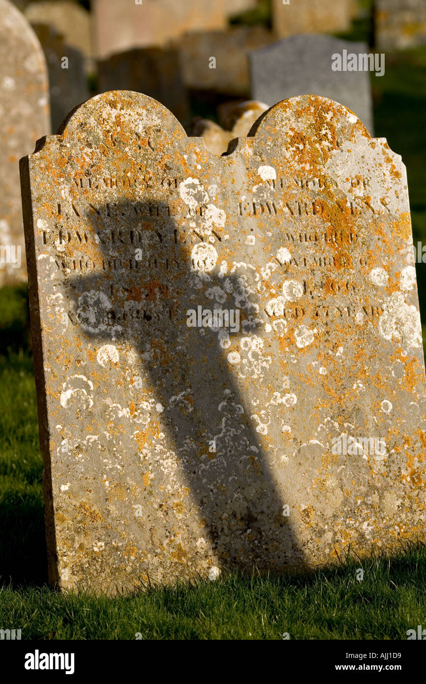 The shadow of cross cast over another gravestone in a Sussex graveyard ...