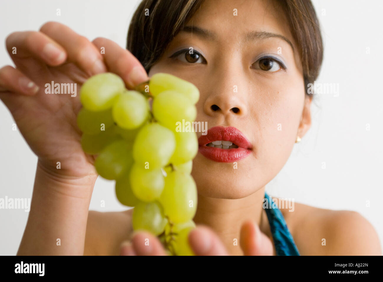 young Korean Asian woman holding a bunch of white grapes Stock Photo ...