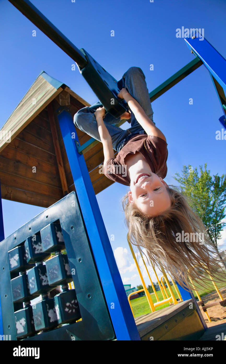 Little girl hanging upside down on playground equipment Stock Photo - Alamy