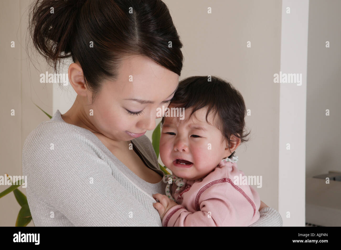Mother holding crying baby Stock Photo - Alamy