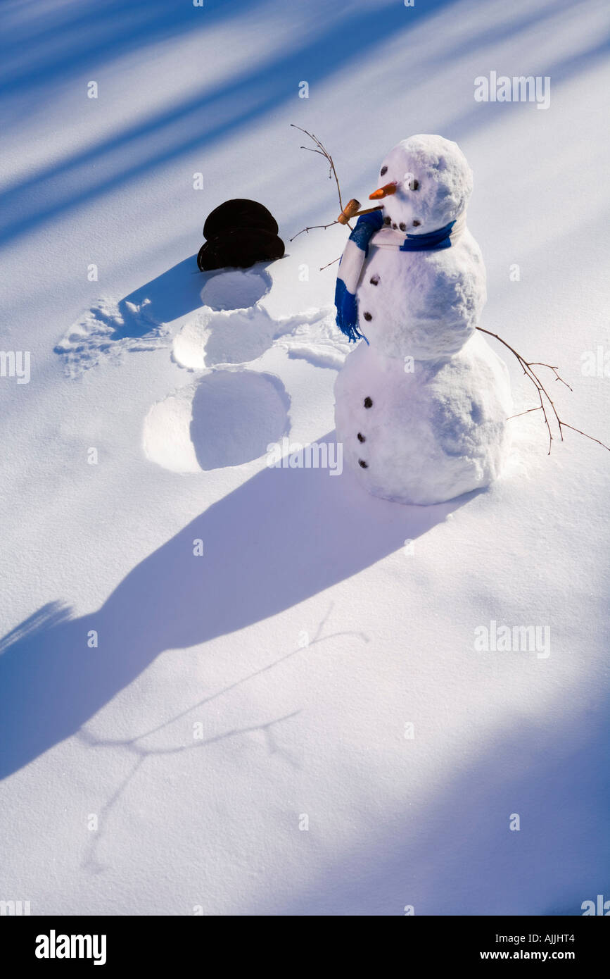 Snowman in forest making snow angel imprint in snow in late afternoon ...