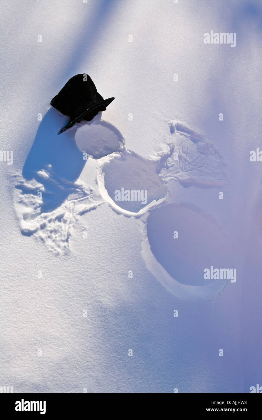 Snowman in forest making snow angel imprint in snow in late afternoon ...