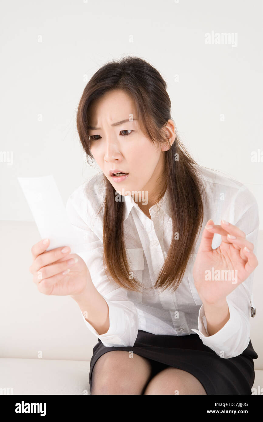 Young woman looking at bill Stock Photo - Alamy