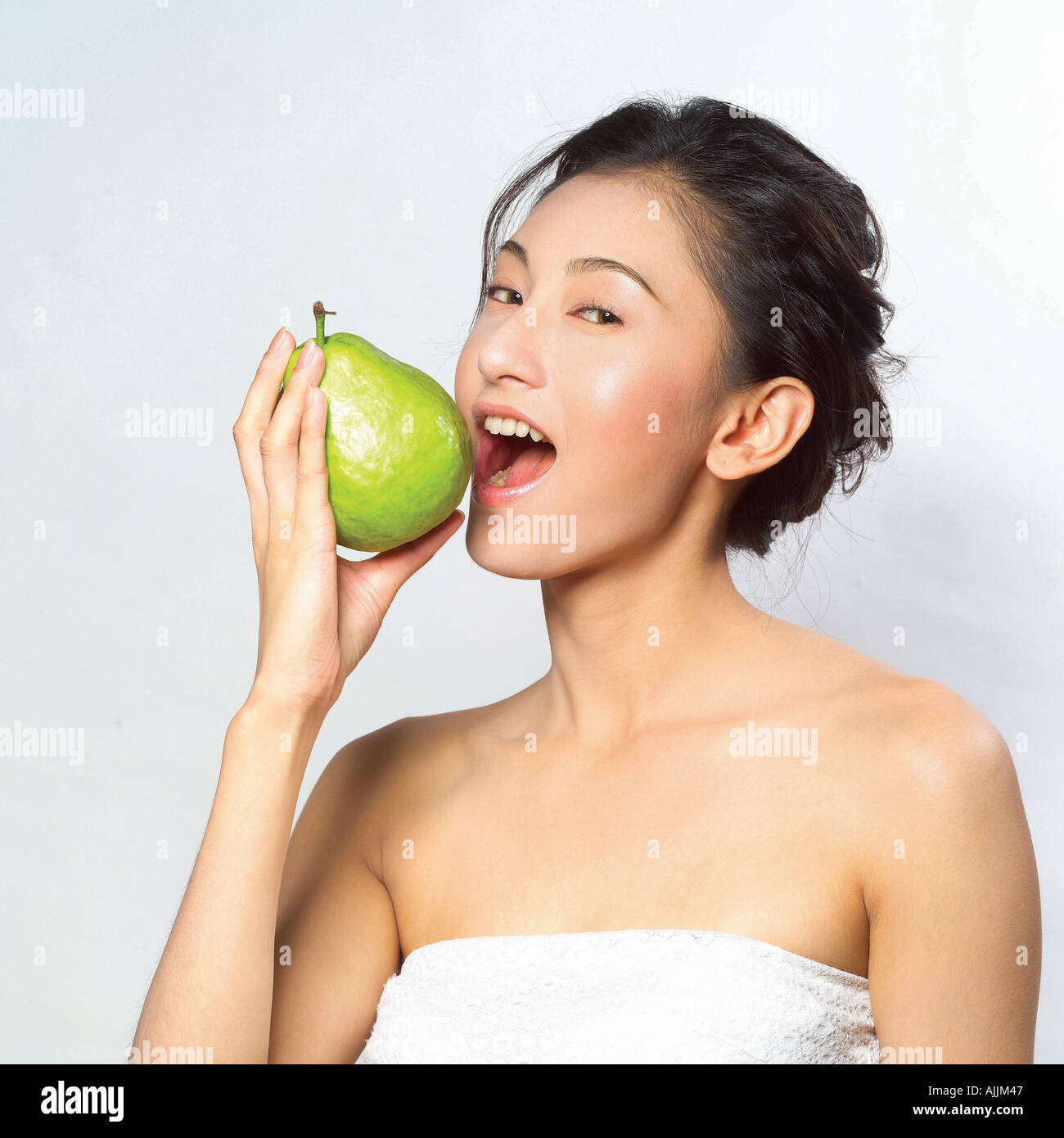 Portrait of a young woman biting into a pear Stock Photo - Alamy