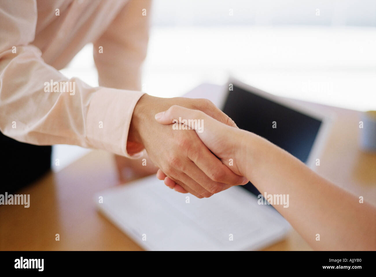Handshake across a desk Stock Photo - Alamy