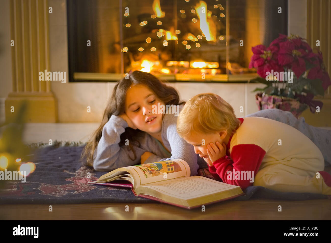 Girls reading book by fire Stock Photo - Alamy