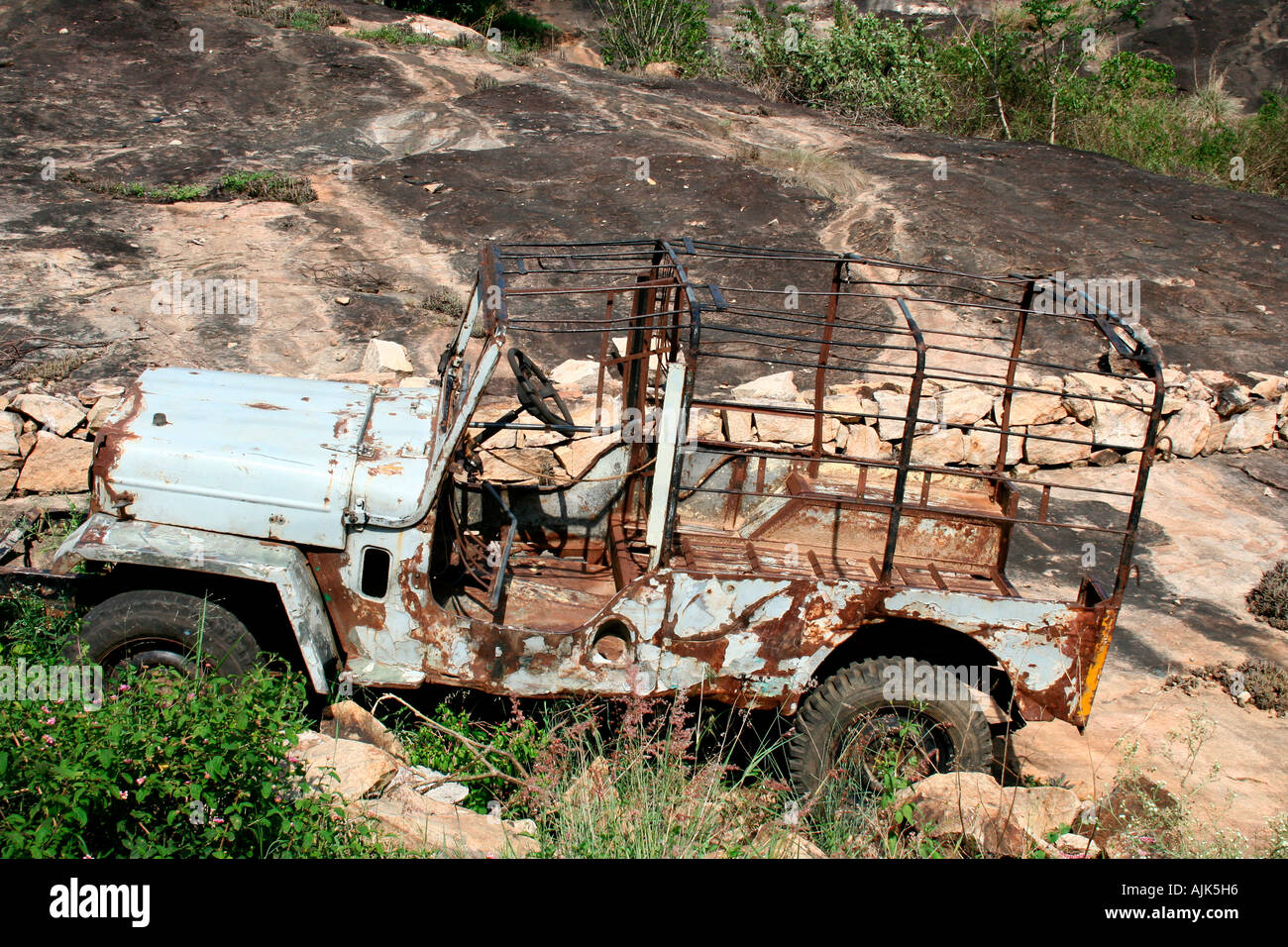 An old damaged jeep abandoned over a rock Stock Photo - Alamy