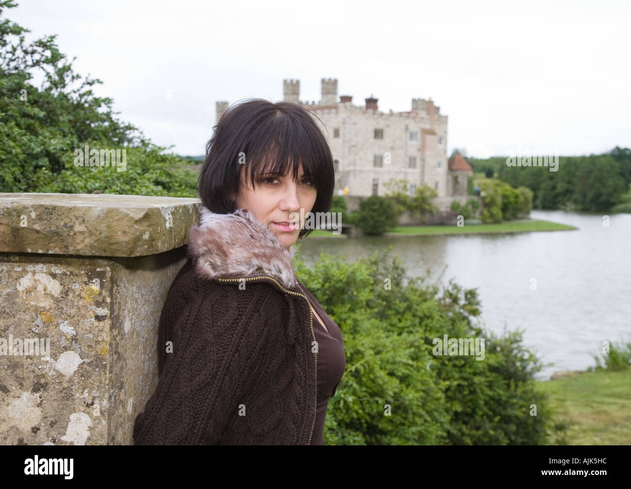 A beautiful girl standing in front of a castle and its mote Stock Photo ...