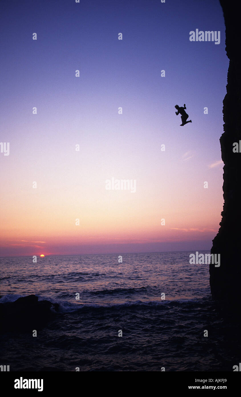 Man takes a running leap off a cliff into sunset Stock Photo - Alamy
