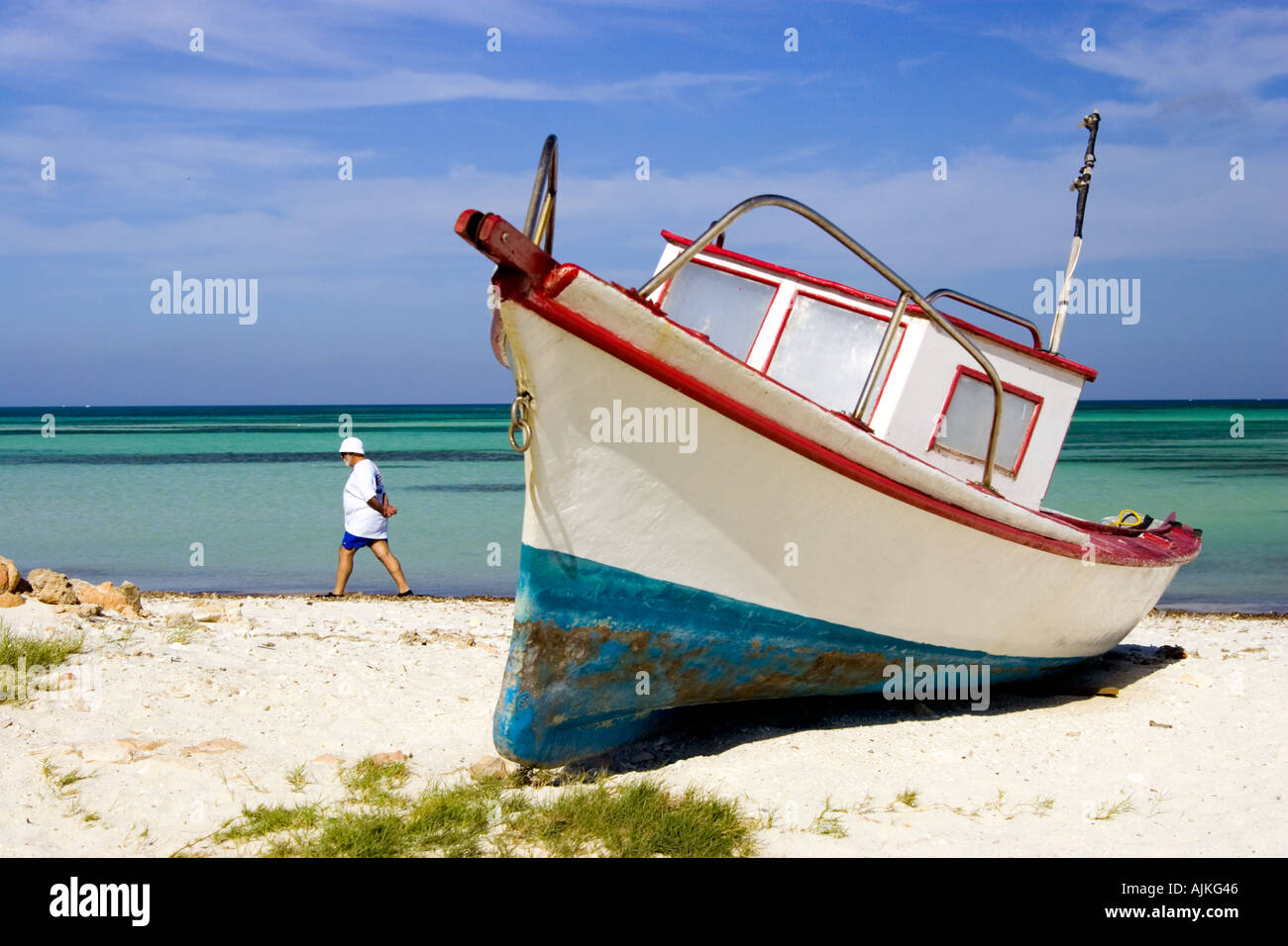 Tourist strolls past beached boat Stock Photo - Alamy