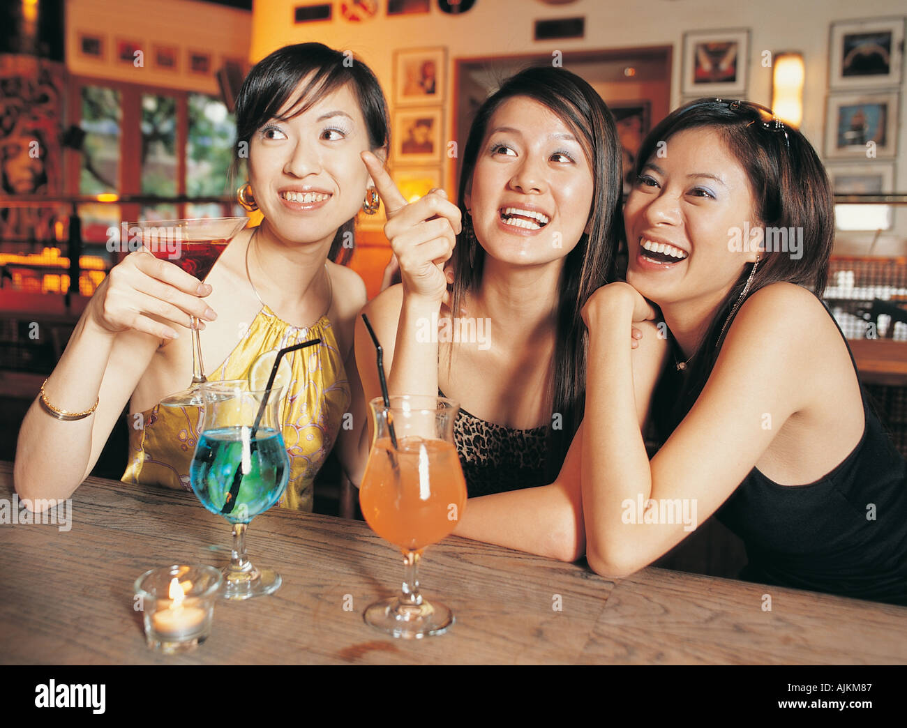 Three young women drinking cocktails in a bar Stock Photo - Alamy