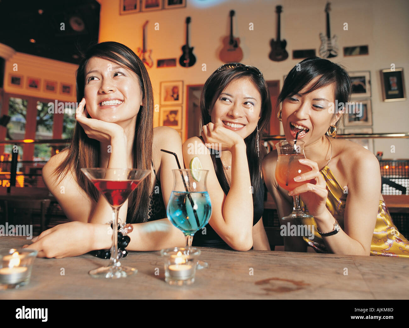 Three young women drinking cocktails in a bar Stock Photo - Alamy