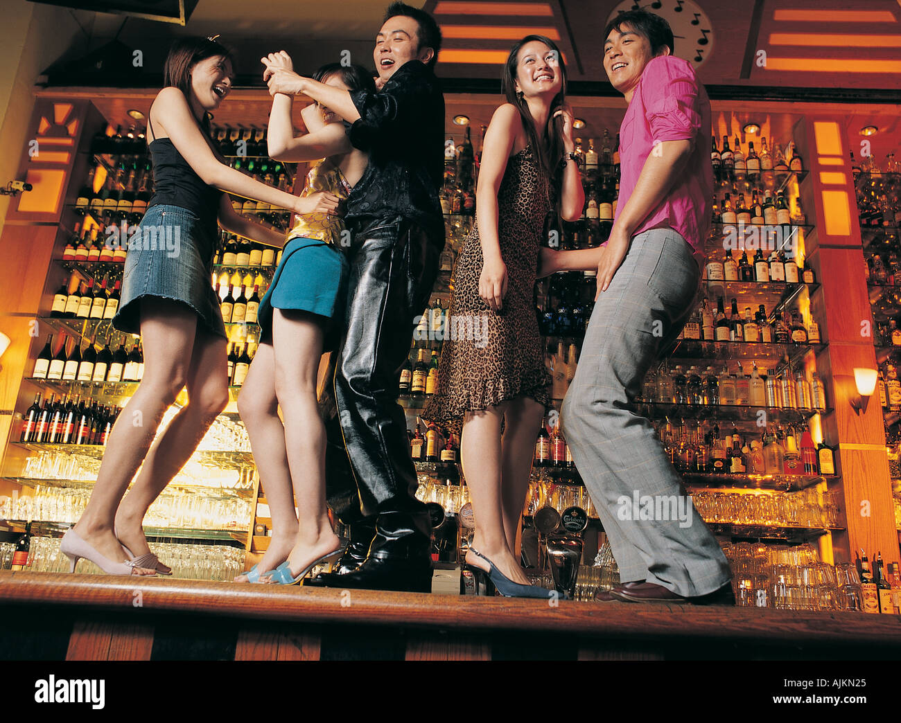 Low angle view of a group of young men and young women dancing on a bar ...