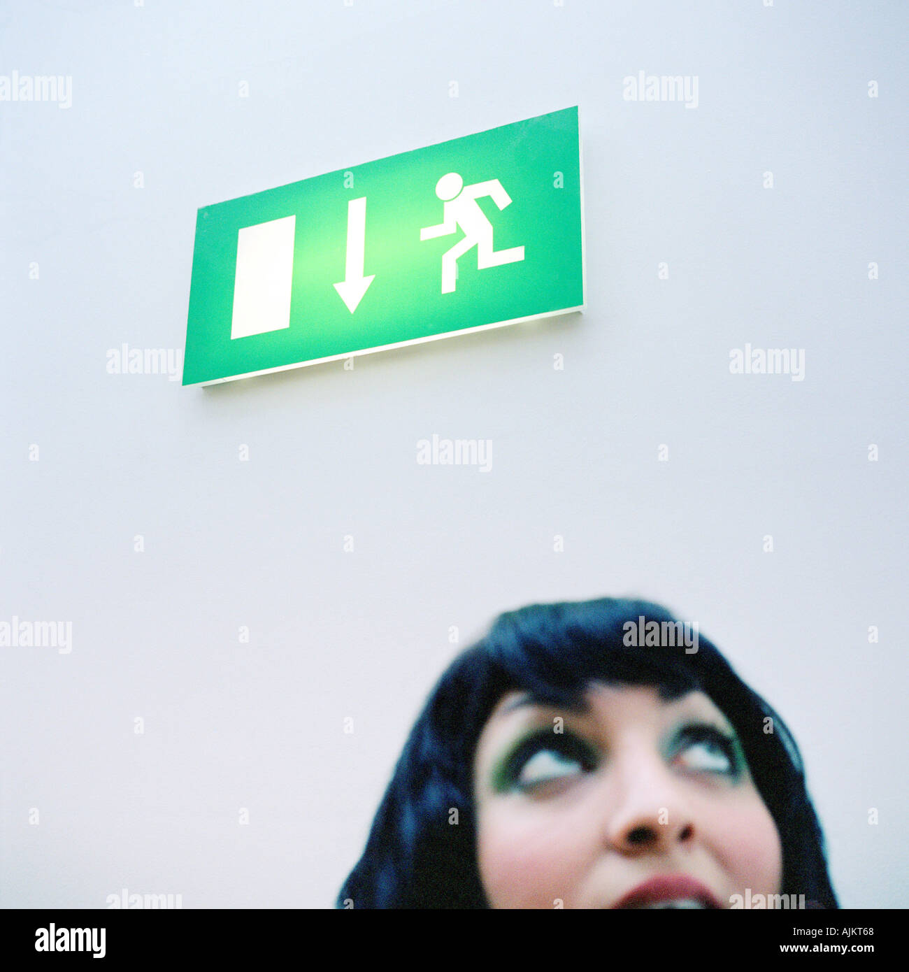 Woman looking toward exit sign Stock Photo - Alamy