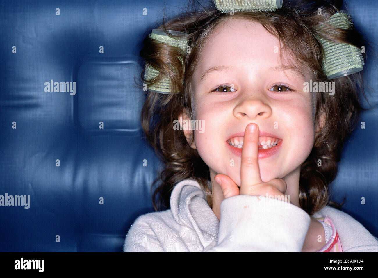 Smiling girl with finger on lips Stock Photo - Alamy