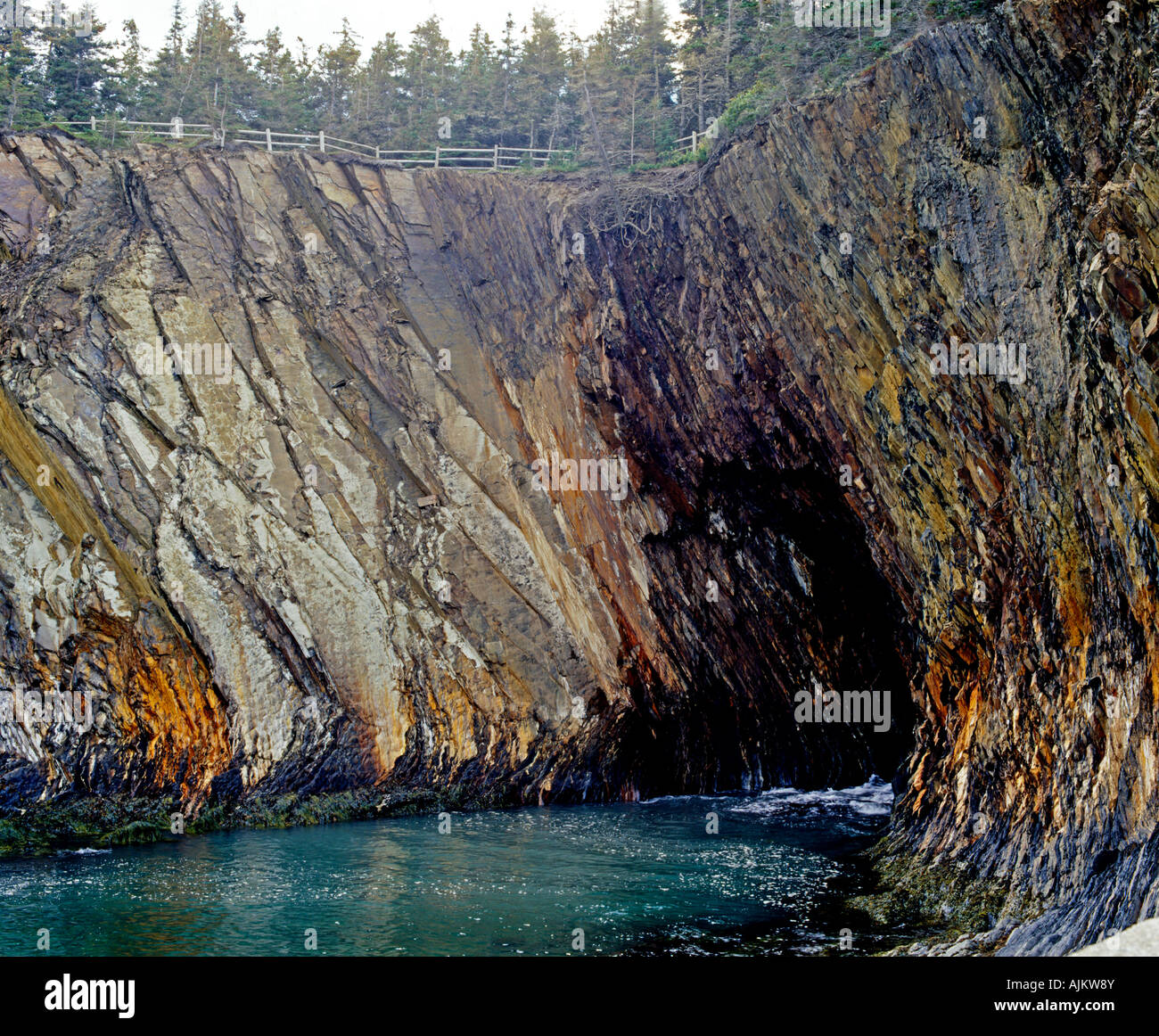 A rock wall leading into a cave with water flowing into it Stock Photo ...