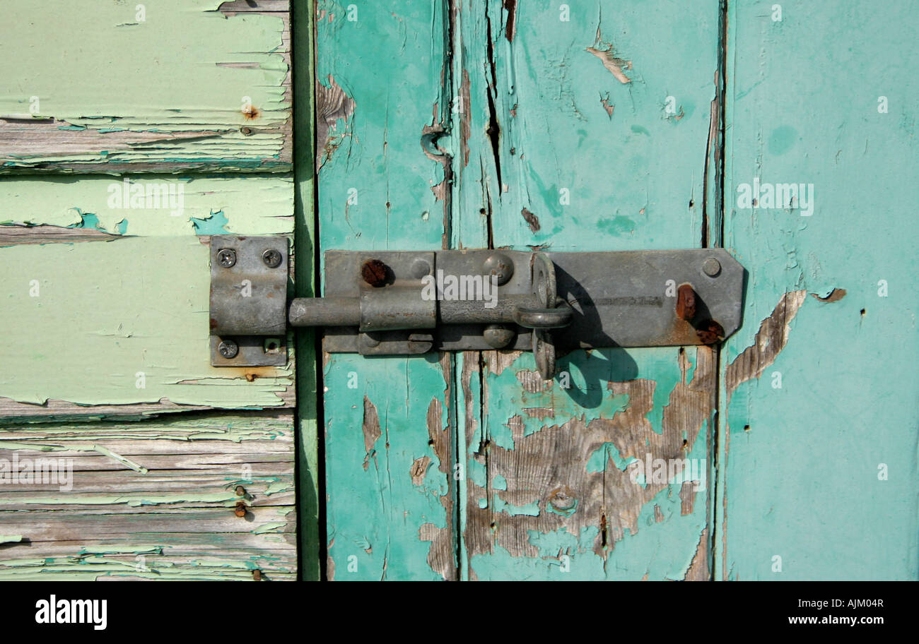 Close up image of a grey bolt on a light greenwooden shed with a ...