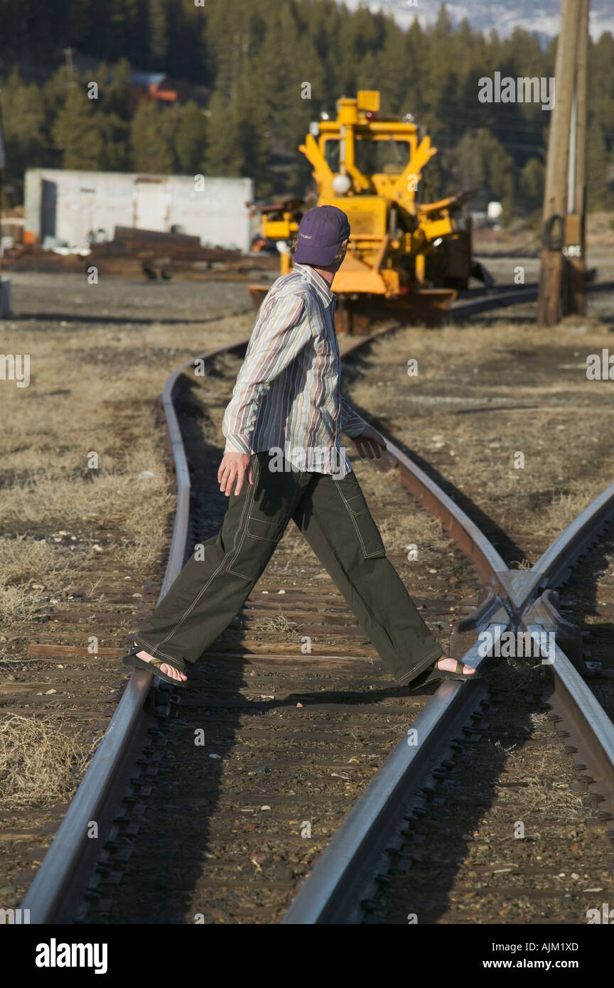 A man walking along and balancing on railroad tracks Stock Photo - Alamy