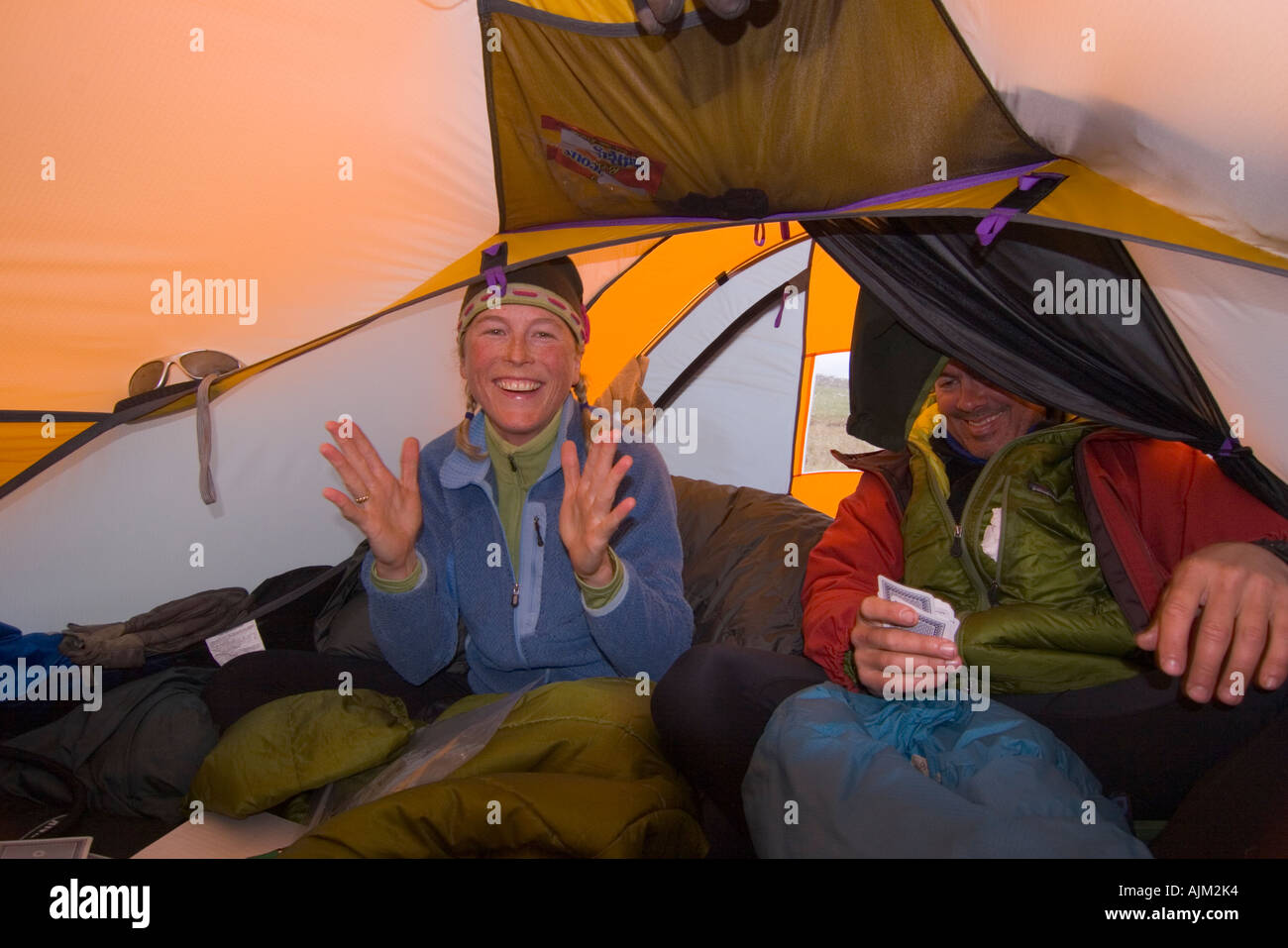 Friends playing cards in a tent while camping in the Aleutian Islands ...