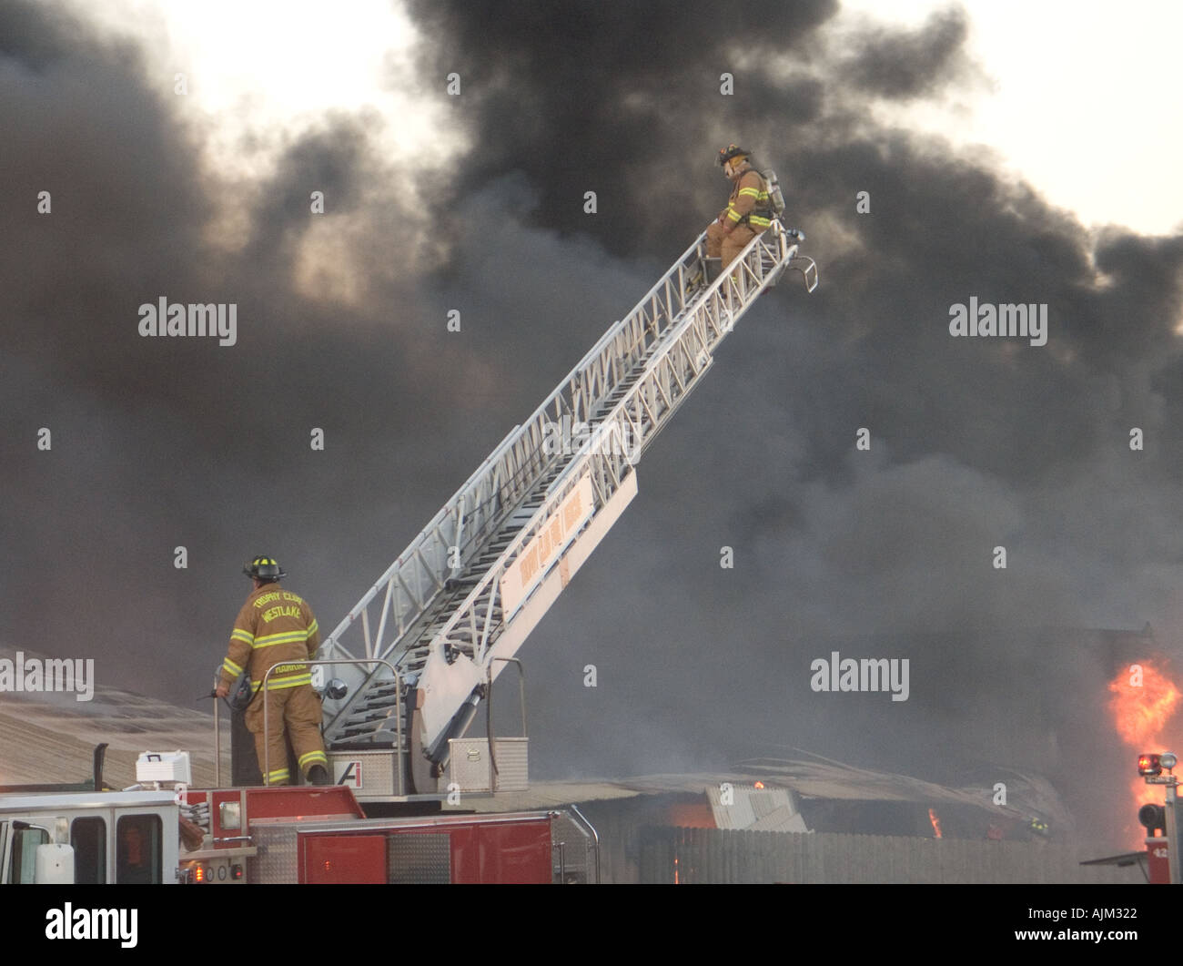 Firemen working a ladder truck during and industrial fire Stock Photo ...