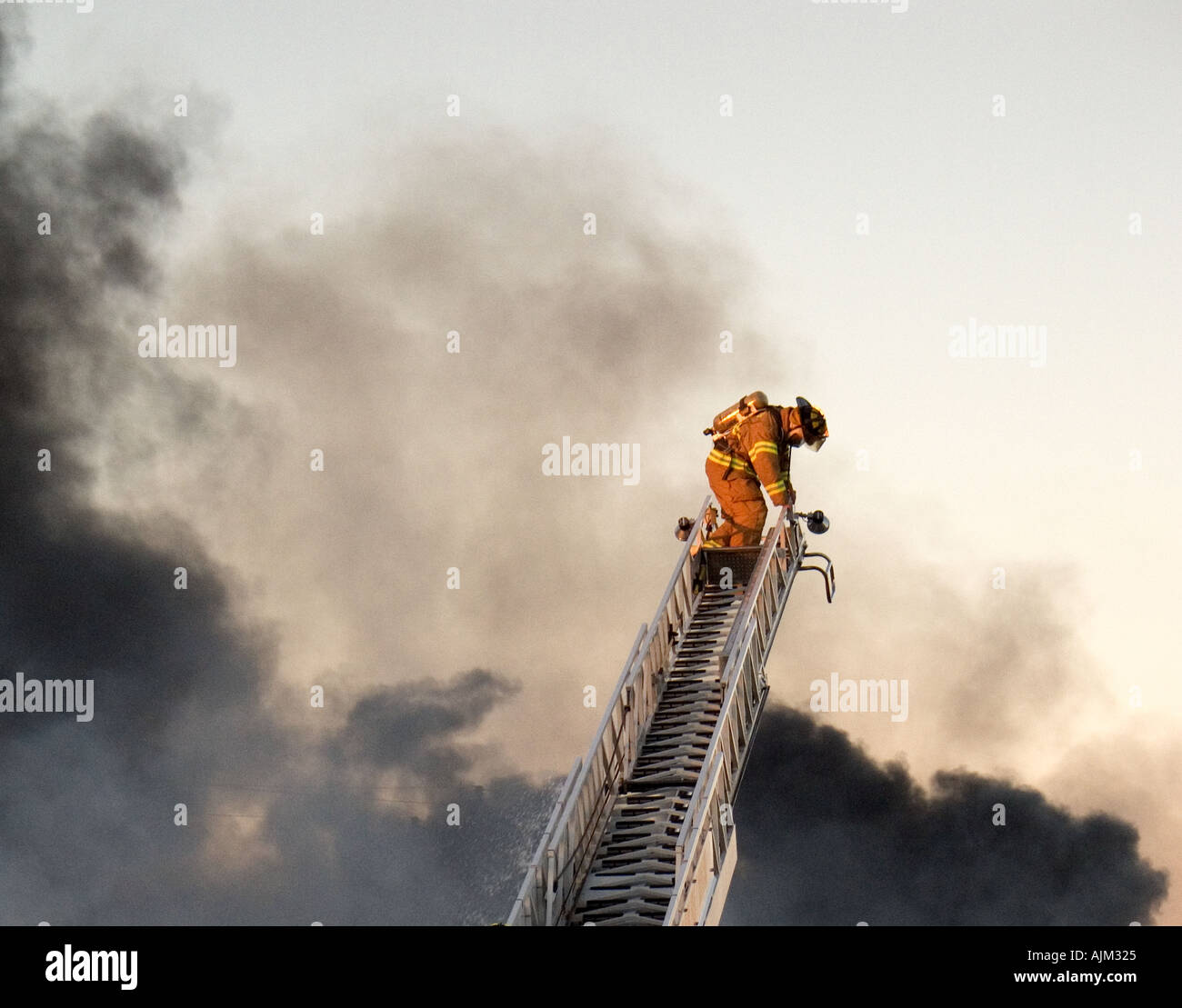 Fireman on top of a ladder fighting an industrial fire Stock Photo - Alamy
