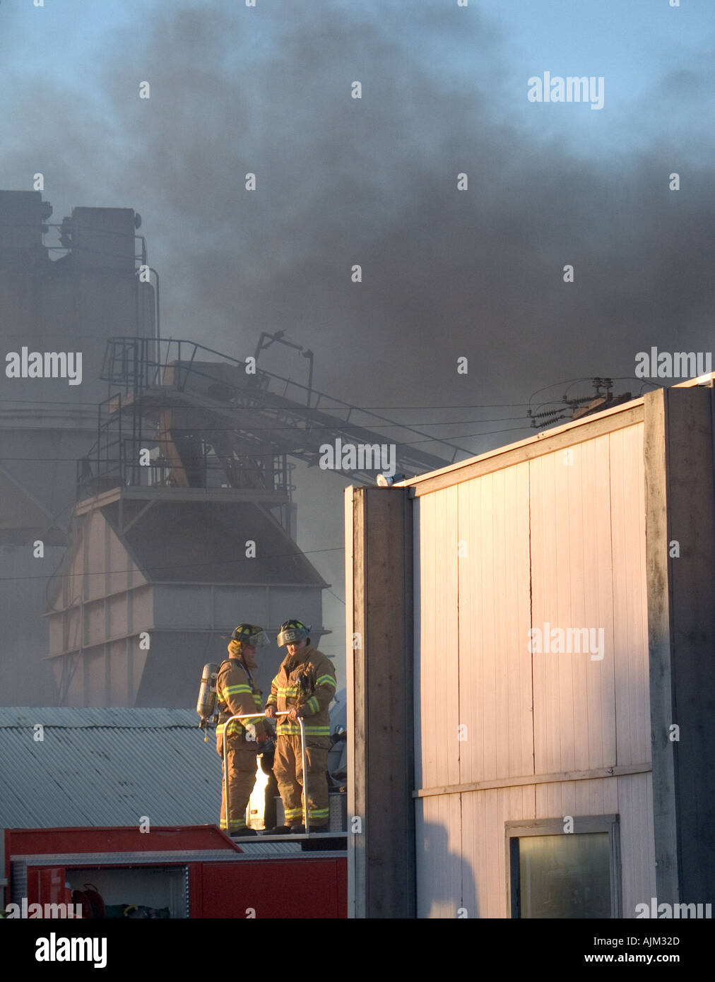 Two firemen at an industrial fire Stock Photo - Alamy