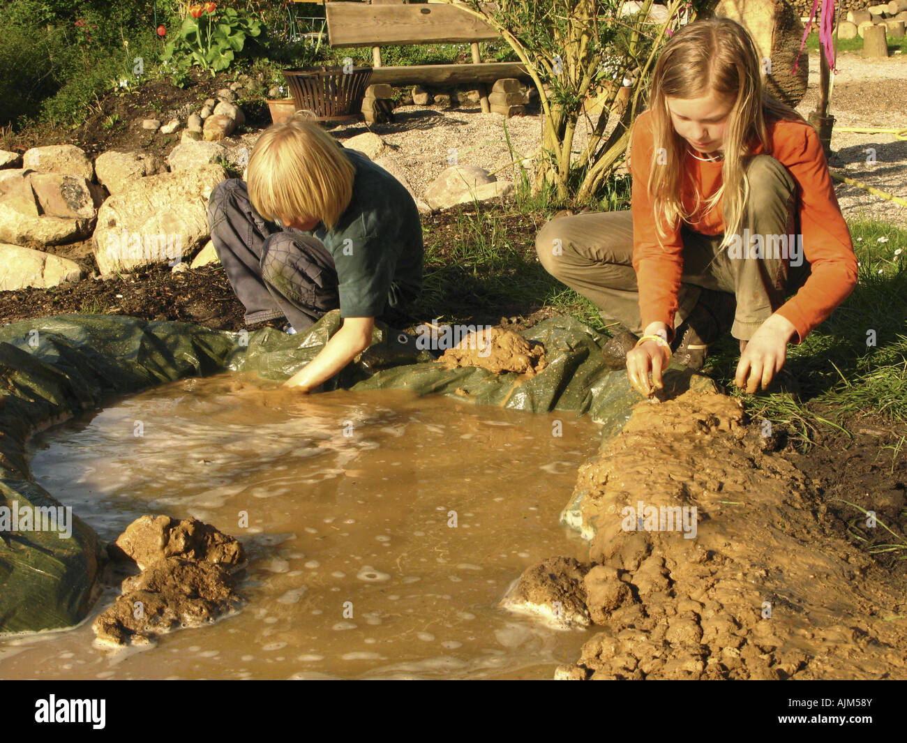 kids build a small pond out of foil and mud in the natural garden Stock ...