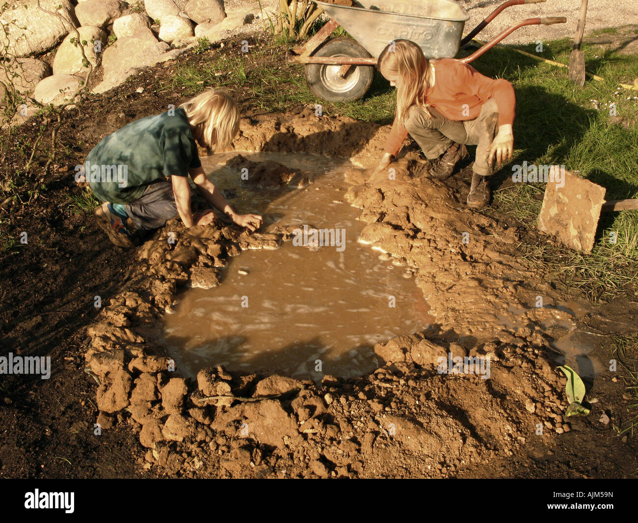 kids build a small pond out of foil and mud in the natural garden Stock ...
