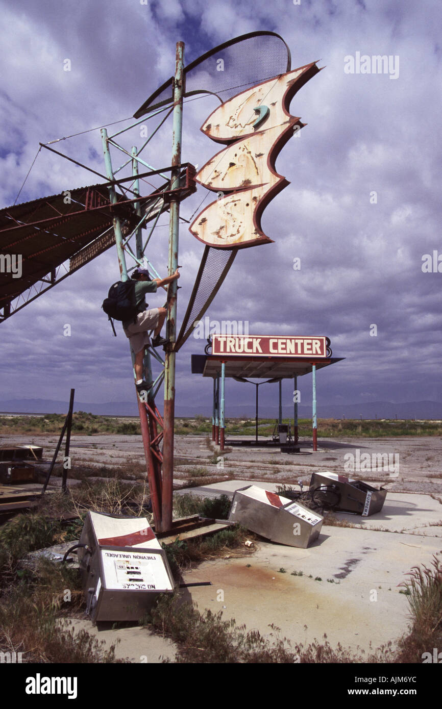 A man climbing an old truck stop sign in the desert near the Bonnevile ...