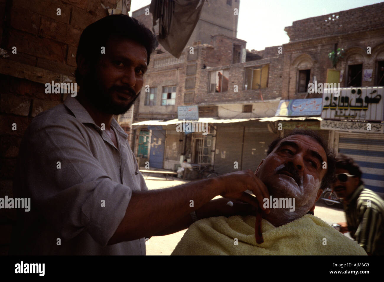 A Pakistani barber shaving a customer on the streets of Rawalpindi ...