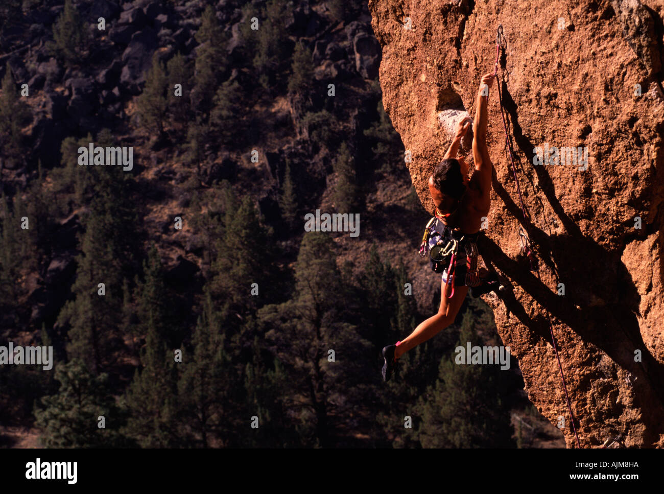 A man rock climbing struggles to clip his rope while climbing a sport ...