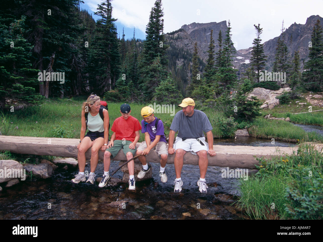 Family of four hikers sitting on a bridge near Dream Lake in Rocky Mtn ...