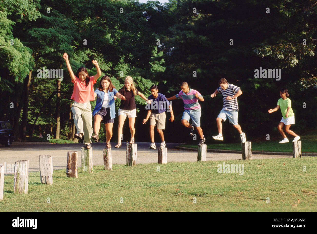 Group of young people balancing on posts at the park Stock Photo - Alamy