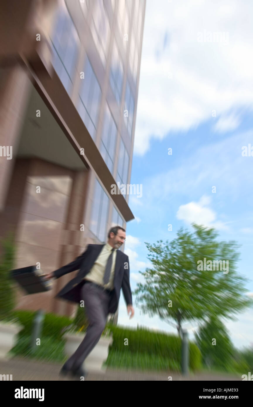 Man leaving building swinging briefcase Stock Photo - Alamy