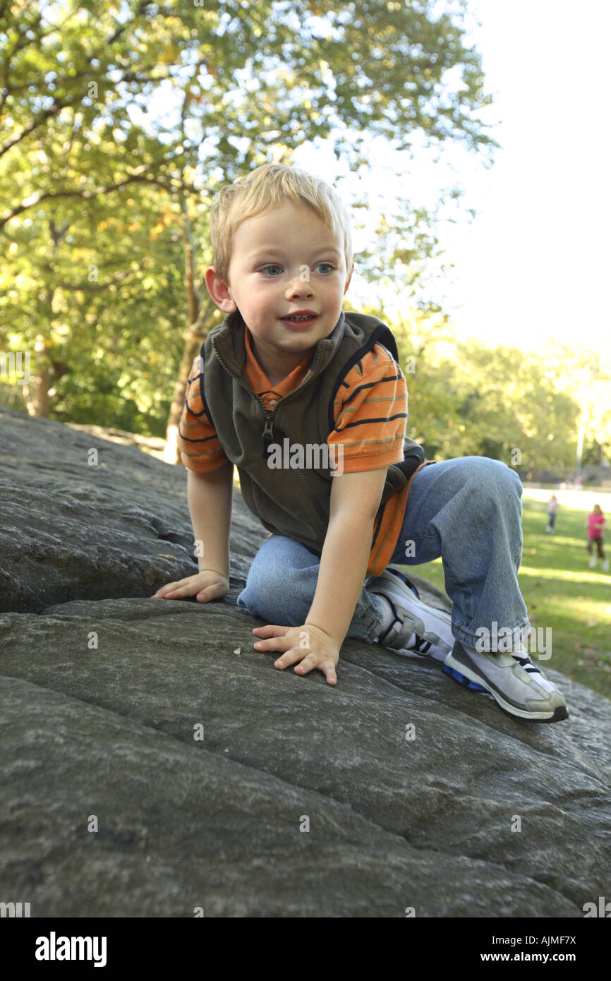 Young boy climbing on rock at Central Park New York City Stock Photo ...