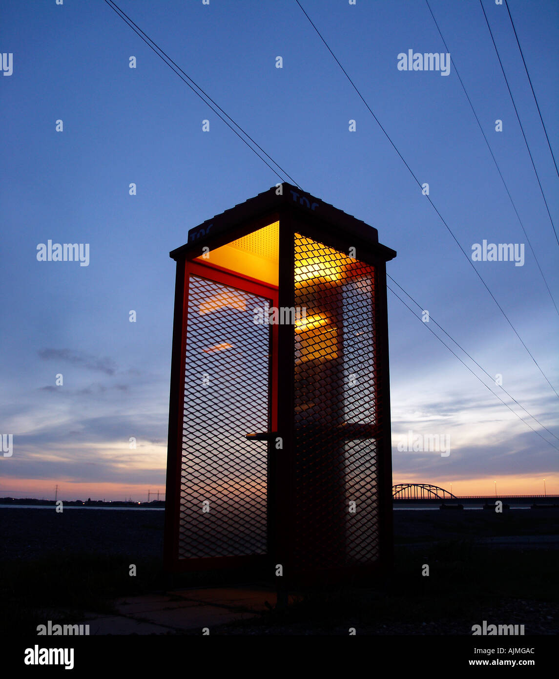 Phone booth at night with powelines in the background symbolising ...