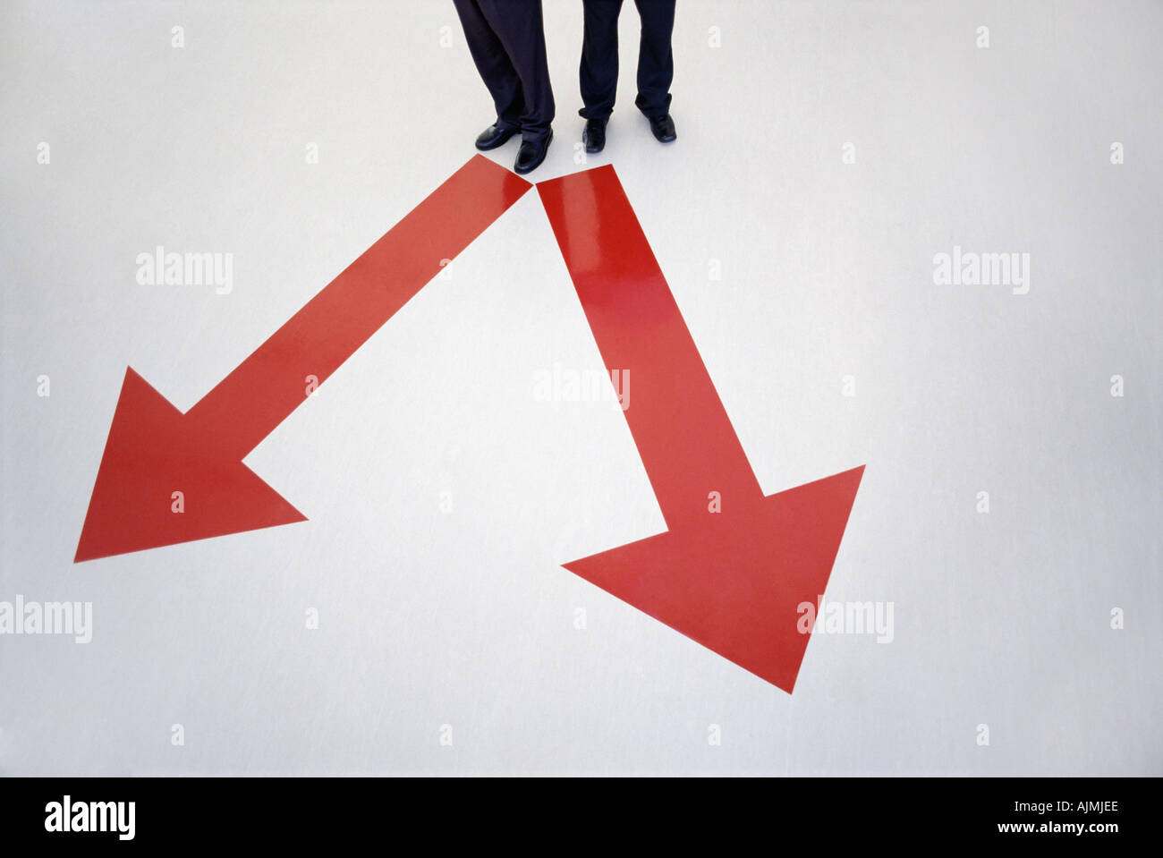 Men standing between direction arrows Stock Photo - Alamy