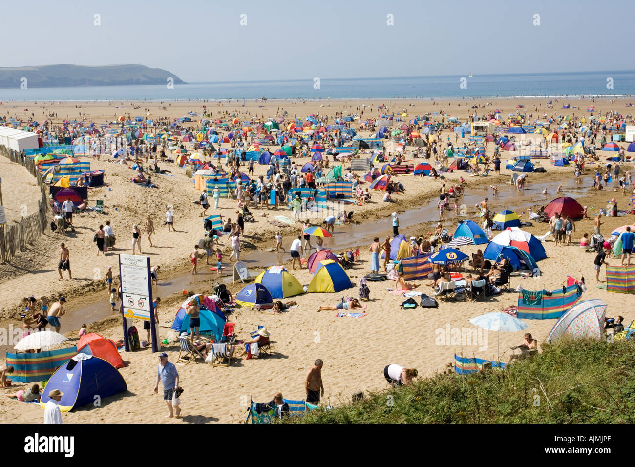 Holidaymakers with tents umbrellas and windbreaks on crowded sandy ...