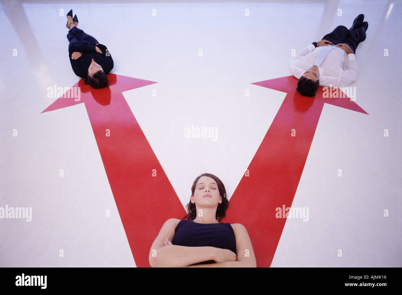 Three people lying on arrow signs Stock Photo - Alamy