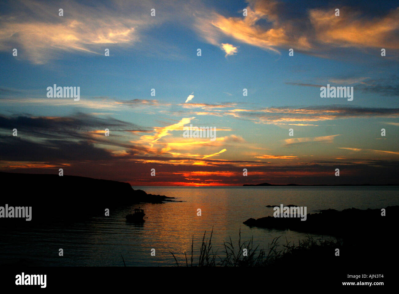 Sunset with fishing boat in St Brides Bay Stock Photo - Alamy