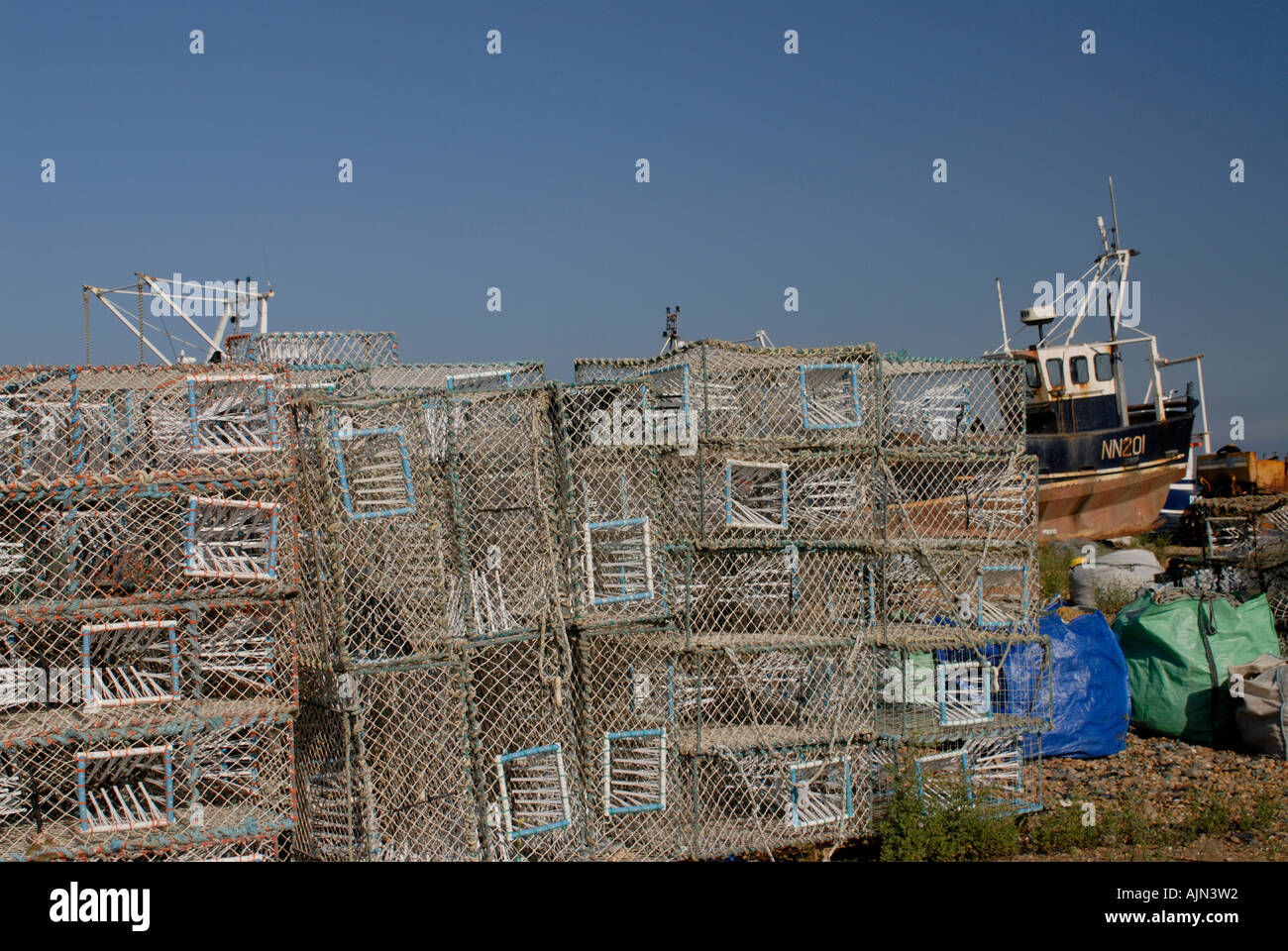 A pile of cuttlefish traps on the beach at Hastings. A fishing boat in ...