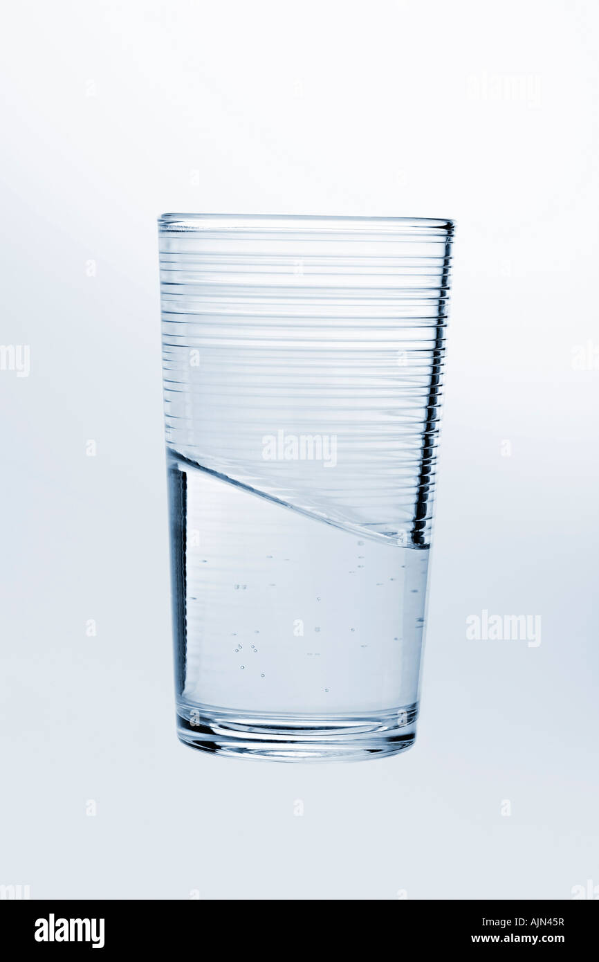 Single glass of water with impossible water level illusion surreal ...
