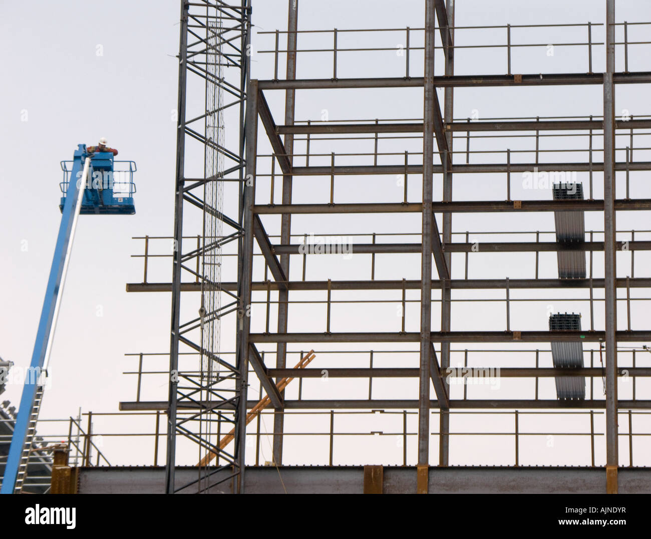 A man on a raised platform works adjacent to a steel girder frame ...