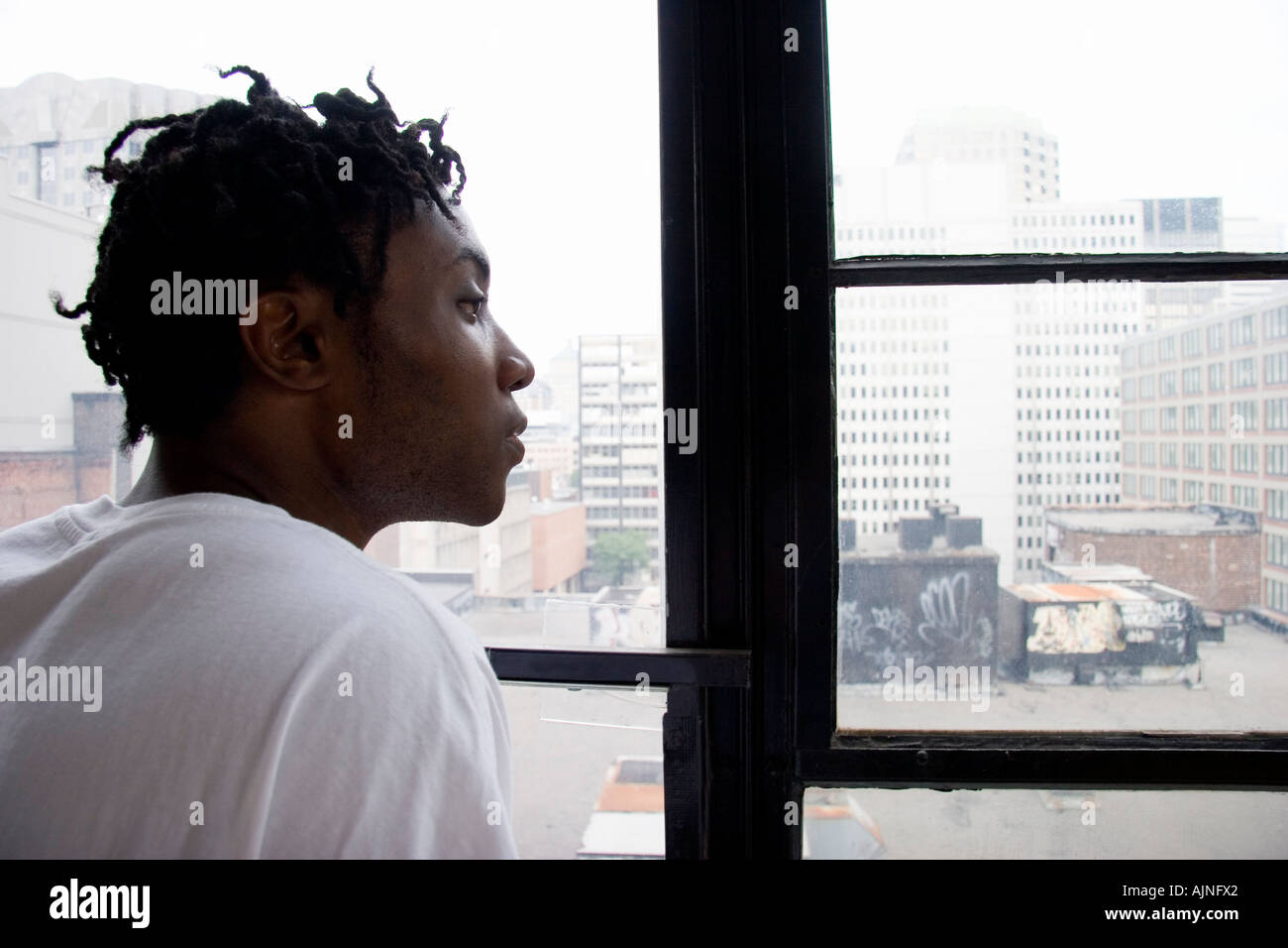 Young man looking out a window Stock Photo - Alamy