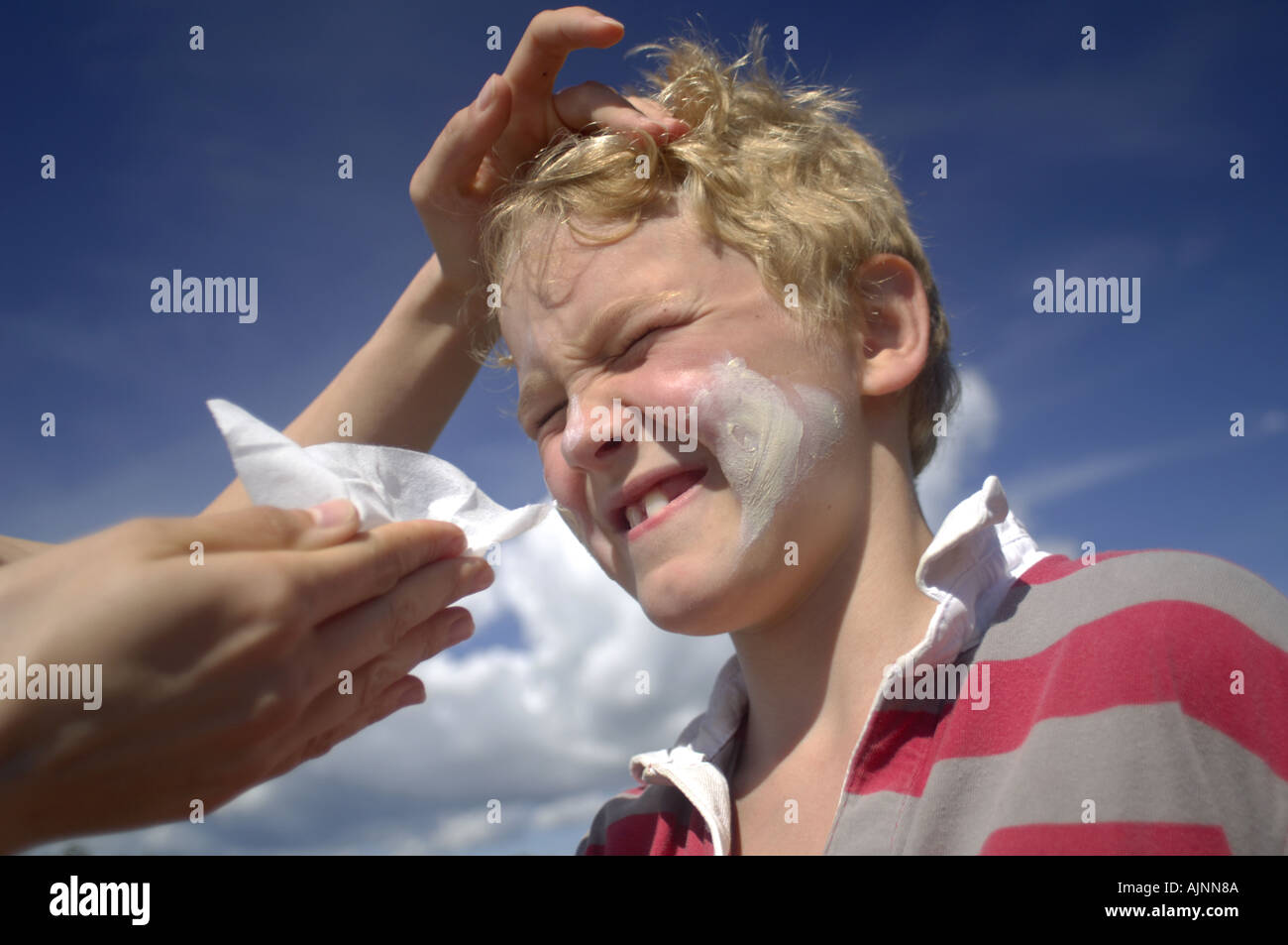 Boy aged 7 having sun cream applied to his face Stock Photo - Alamy
