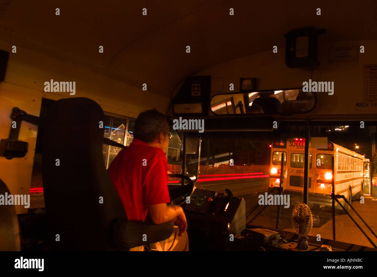 School bus driver at night at a fair looking out his front window at ...