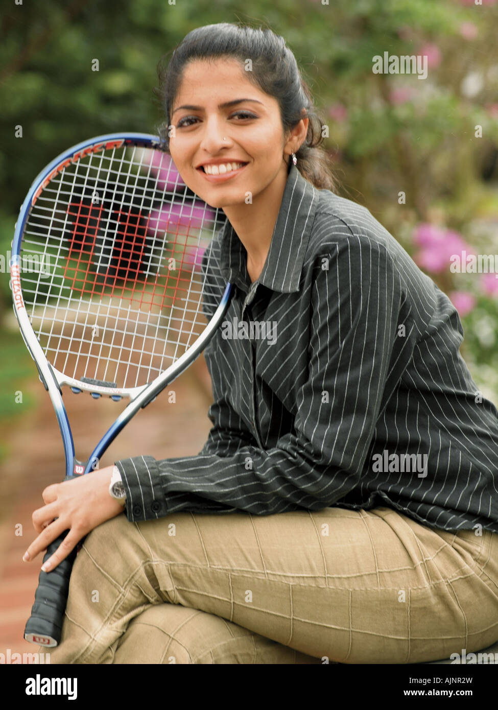 Portrait of a young woman holding a tennis racquet Stock Photo - Alamy