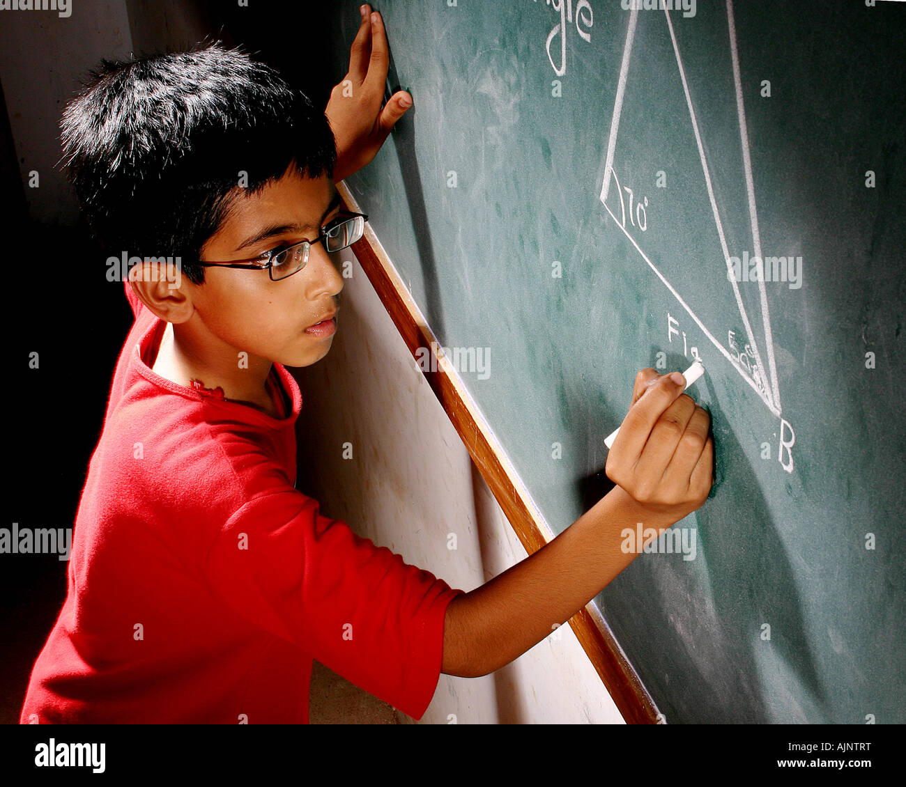 A boy drawing a triangle on a blackboard Stock Photo - Alamy