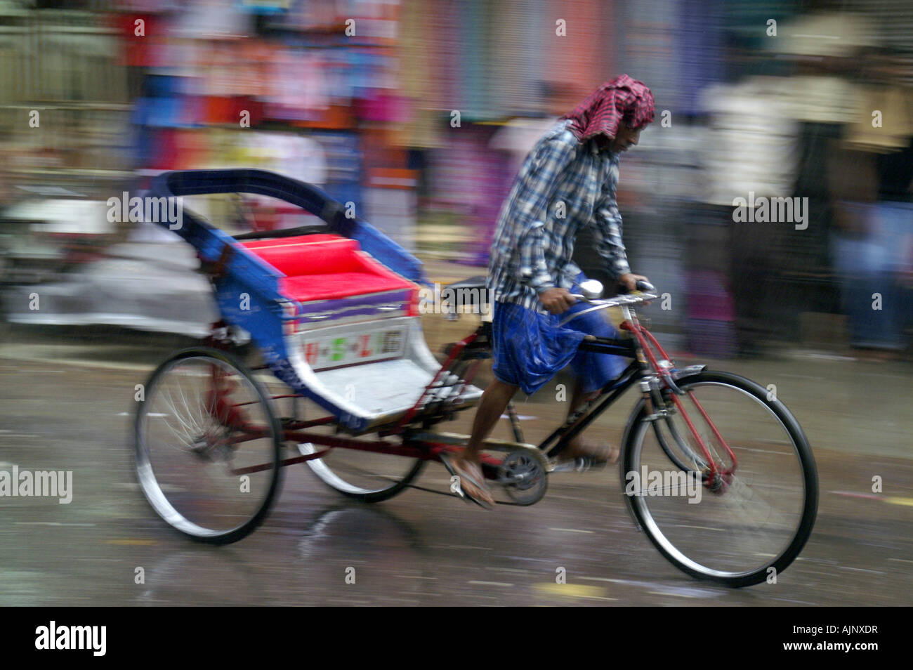 Rickshaw speeding rain street New Delhi cycling fast motion blur India ...